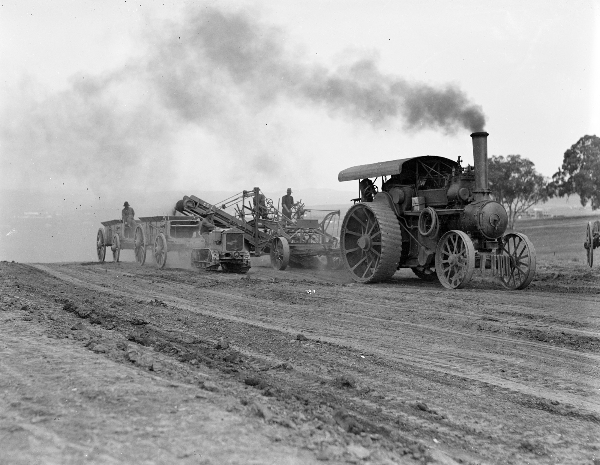 Traction engine towing a road grader loading a wagon and a Cletrac ...